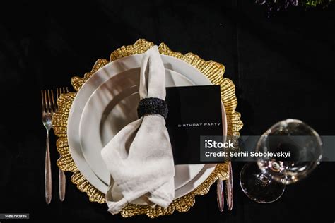 초대장 생일 파티 손님 좌석 텍스트 공간 금색 장식이 있는 린넨 냅킨이 있는 흰색 접시 검은색 식탁보에 와인잔 설정 세부 정보 테이블 세팅 서빙 평면도 근접 촬영 0명에