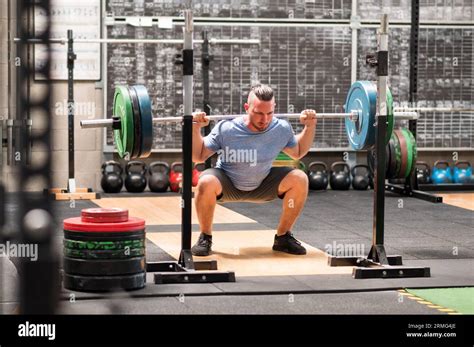 Full Body Of Determined Male Athlete In Sportswear Doing Back Squats