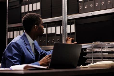 Premium Photo African American Officer Looking At Shelves Full With Police Documents