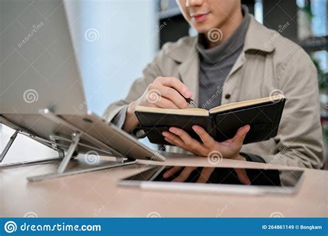 Smart Asian Male Programmer Or Web Developer Concentrating On His Task Taking Notes Stock Image