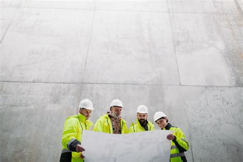 Team Of Engineers And Construction Workers Reviewing Blueprints