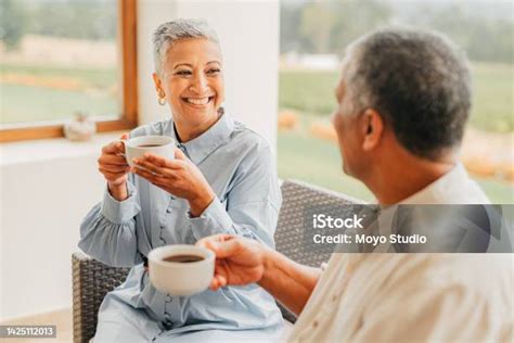 노인 부부는 봄철에 집에서 야외에 앉아있는 동안 정원에서 커피를 마신다 행복한 노인 결혼 남녀가 안뜰에서 따뜻한 음료를 마시 며 대화를 나눕니다 노인 커플에 대한 스톡 사진