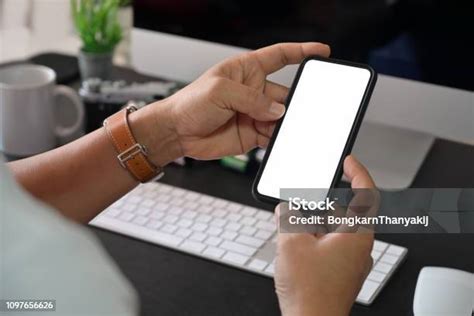 데스크톱 컴퓨터와 함께 작업 하는 동안 빈 화면이 휴대 전화를 들고 크리에이 티브 세련 된 손 스마트폰에 대한 스톡 사진 및 기타 이미지 Istock