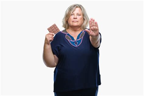 수석 플러스 크기에 초콜릿을 먹는 백인 여자와 배경 절연 열 심각 하 고 자신감 표현 방어 제스처 정지 표시를 하 고 손을 경계