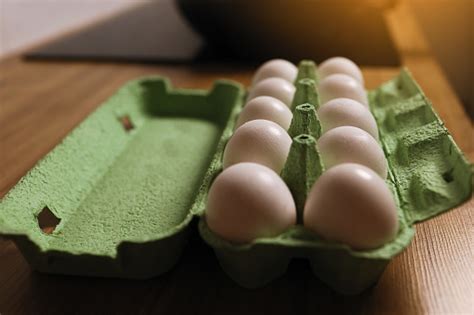 나무 테이블 배경에 녹색 판지 계란 트레이에 있는 12개의 흰색 신선한 닭고기 계란 열린 판지 팩 또는 계란 용기에 담긴 신선한 유기농 계란 영양가있는 음식 농장 제품 개념