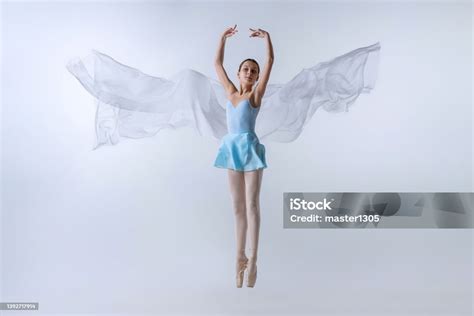 한 어린 소녀 파란 드레스를 입은 발레리나 지망생과 회색 배경에 고립 된 천으로 춤을 추는 것을 가리킨다 예술 은혜 아름다움