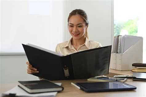 매력적인 여성 직원이 재무 문서를 확인하고 사무실 책상에서 통계를 가지고 작업합니다 20 24세에 대한 스톡 사진 및 기타 이미지 20 24세 25 29세 30 34