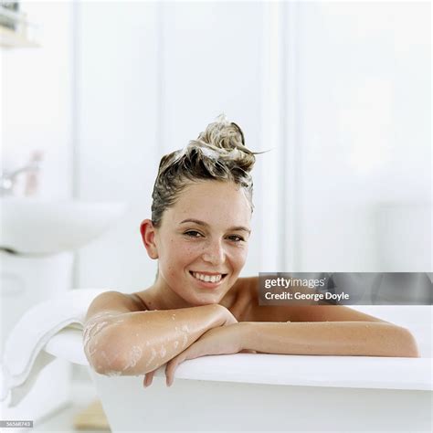 Portrait Of A Young Woman Sitting In A Bathtub With Shampoo In Her Hair