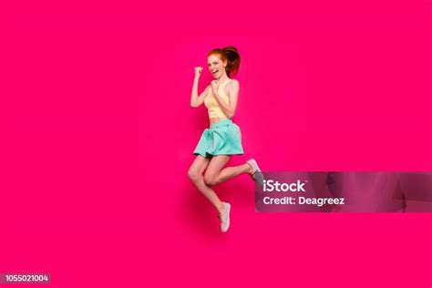 매력적인 긍정적인 장난 다행 빨간 머리 여자 Tanktop와 포니 테일 승리 몸짓 짧은 스커트에 공기 점프의 전체 몸 길이 크기