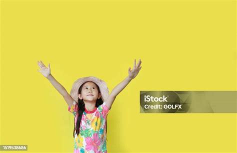 아시아의 어린 소녀는 복사 공간이 있는 노란색 배경에 고립된 채 두 팔을 크게 벌리고 있다 꽃무늬 여름 드레스와 모자를 쓴 아이 휴일과 여름 패션 컨셉 4 5세에 대한 스톡