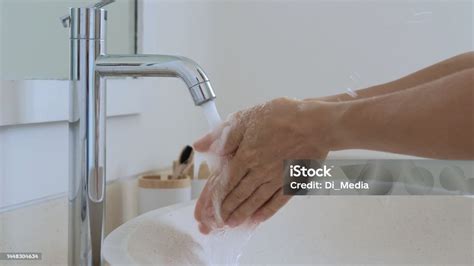 욕실의 수도꼭지를 켜고 피부 표면의 먼지 및 기타 물질을 제거하기 위해 물로 손을 닦는 위생 절차를 수행하십시오 위생 및 손 씻기 감기와 독감에 대한 스톡 사진 및 기타