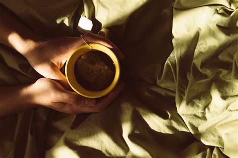 노란 침대 이불에 티백을 곁들인 차 한 잔을 마시는 여성의 손 가정 생활에 대한 스톡 사진 및 기타 이미지 가정 생활 노랑