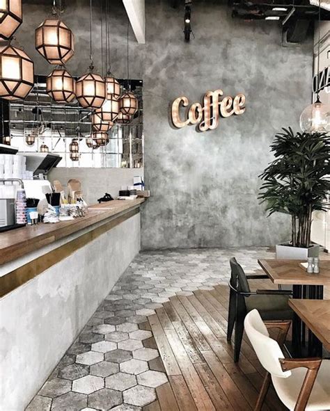 The Interior Of A Coffee Shop With Wooden Tables And Chairs Hanging Lights And Potted Plants