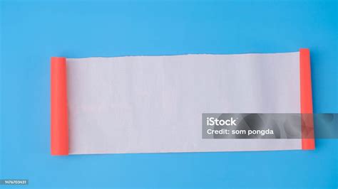 주황색 압연 사각형 용지가 연한 파란색 배경에 빈 흰색 시트로 펼쳐져 있습니다 텍스트 또는 광고 공간을 위한 복사 공간이 있는