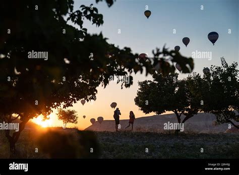 a couple taking photos with floating air balloons on the sunrise stock