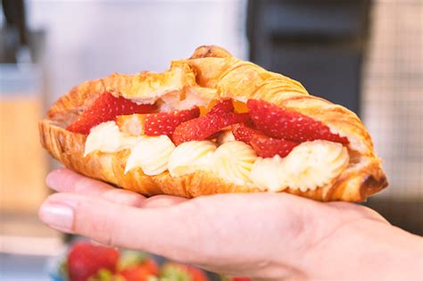 달콤한 휘핑 크림과 신선한 딸기 슬라이스와 함께 맛있는 박제 크루아상을 들고 있는 인간의 손 0명에 대한 스톡 사진 및 기타 이미지 Istock