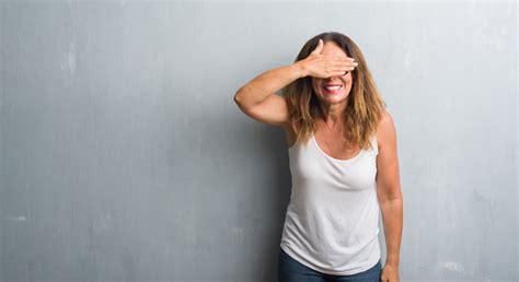 중세 스페인 여자 선글라스 웃 고 손으로 덮고 눈 깜짝 하는 얼굴에 웃음을 입고 회색 벽에 눈 먼 개념입니다 가리기에 대한 스톡