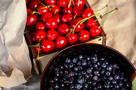 블루베리와 상자의 자른 그릇 공예 주름 오래된 종이 배경에 꼬리와 빨간 달콤한 체리의 크레이프 수확 및 작물 개념 유기농 식품 여름철 맨 위 보기입니다 여름 과일 0명에