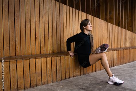 A Girl In A Black Sports Uniform Does Reverse Push Ups With Support On