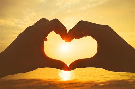 海に落ちていく夕陽にハートの手をかざす女の子 オレンジ版 の画像｜おしゃれなフリー写真素材：girly Drop