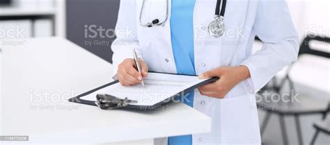 직장에서 알 수 없는 의사 여자 손 클로즈업 진료소 또는 응급 병원에서 리셉션 데스크 근처에 서 있는 동안 여성 의사는 의료