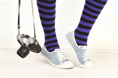 Premium Photo Girl In Sneakers With Retro Photo Camera In Room