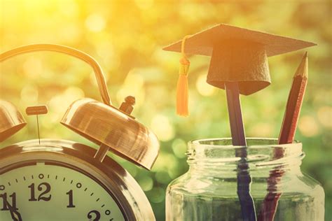 교육에서 가장 강력한 무기 또는 지식 파워 개념 검은 졸업 모자 또는 모자 술 빨간색과 파란색 연필 시계 근처와 투명 유리 항아리 나 병에 연필에 달려있습니다 재회 사회적