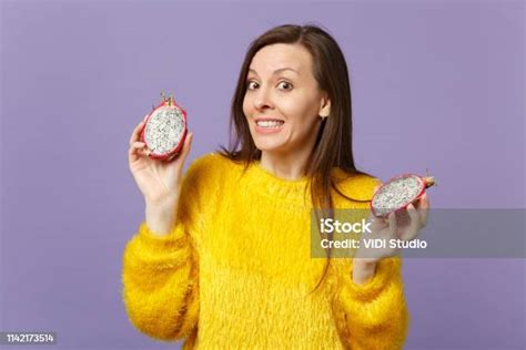 신선한 잘 익은 피타 하 야 보라색 파스텔 배경에 고립 된 드래곤 과일의 Halfs 손을 잡고 모피 스웨터에 젊은 여자를 의아해 사람들은 생생한 라이프 스타일 휴식 휴가