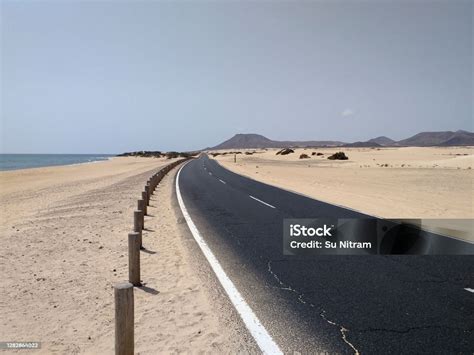 모래 언덕 화산 사막 의 풍경과 조용한 바다 사이의 곡선 아스팔트 도로의 관점보기 목가적 인 풍경 배경의 외로운 길 0명에 대한