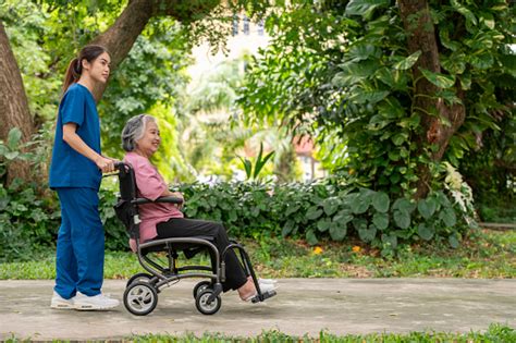 휠체어에 앉아있는 노인 여성과 젊은 간병인 또는 의료 종사자가 뒤에 서 있는 것은 보살핌 연민 및 지원 관계인 간병인과 노인의