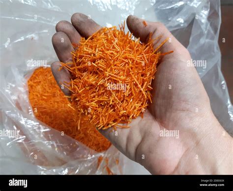 A Closeup Of A Person Holding Orange Plastic Recycled Pellets Stock
