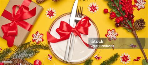 밝은 노란색 배경에 빨간 리본 선물 전나무 가지 솔방울 및 장식용 눈송이로 묶인 접시와 칼 붙이가 있는 축제 구성 0명에 대한 스톡 사진 및 기타 이미지 Istock