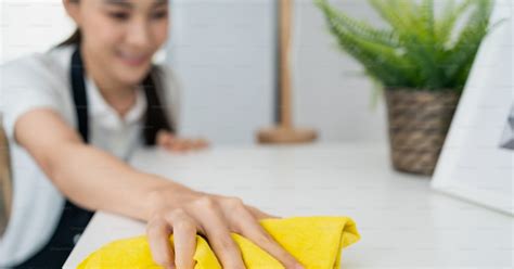 집에서 거실에서 청소하는 아시아 청소 서비스 여성 노동자 아름다운 소녀 주부 가정부 청소부는 행복하다고 느끼고 가사 가사 또는 집안일을 위해 지저분한 더러운 작업 테이블을