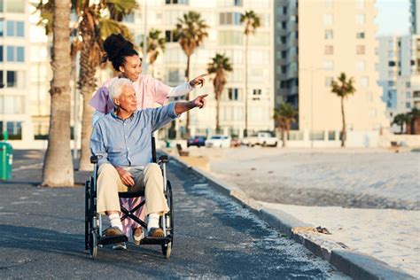 매력적인 젊은 여성 간호사가 휠체어를 타고 도시 주변을 노인 환자를 밀어내는 전체 길이의 샷 20 24세에 대한 스톡 사진 및 기타 이미지 Istock