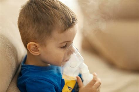 소년은 약을 폐로 흡입하는 분무기로 흡입합니다 프리미엄 사진