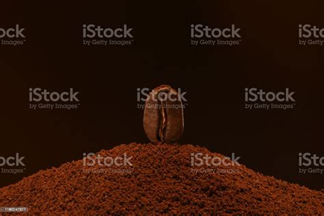 갓 구운 커피 콩은 갈색 배경에 한 줌의 분쇄 커피위에 서 있습니다 격리된 매크로 엽서 배너 공간을 복사합니다 갈색에 대한 스톡