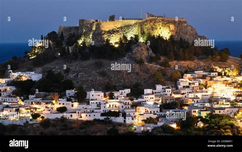 Night View Of An Illuminated Fortress Above A Quiet Village With