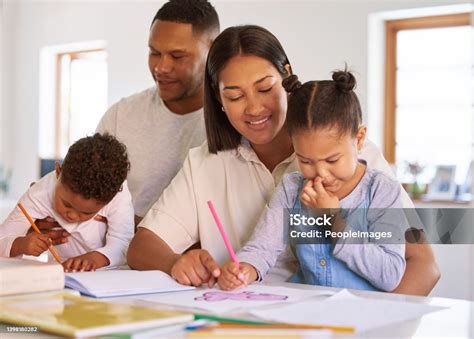 소년과 소녀는 엄마와 아빠와 함께 홈 스쿨을 통해 배우고 공부합니다 혼합 인종 커플은 색칠 숙제 및 과제로 두 어린 아이들을 돕습니다 집에서 자녀를 가르치는 부모 교실에