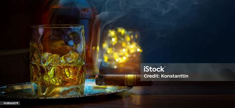 나무 테이블에 얼음이 든 위스키 한 잔 김이 나는 쿠바 시가 나이트 바의 연기가 자욱한 분위기의 위스키 한 병 0명에 대한 스톡