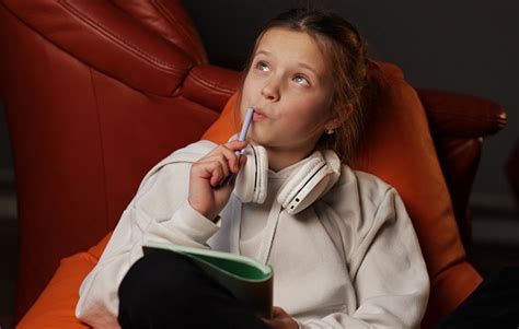 헤드폰을 어깨에 메고 10대 초반의 여고생이 집에서 공부하며 필기를 하고 있다 초등학생이 연습장에 쓰고 숙제를 하고 가정