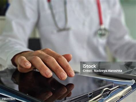 흰 가운을 입은 의사 손을 잡고 현대 디지털 태블릿 Pc를 사용하여 사무실 책상에 청진기를 놓고 노트북 컴퓨터에서 작업합니다 40 44세에 대한 스톡 사진 및 기타 이미지