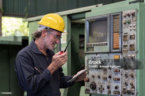 공장에서 제어 기계를 위한 디지털 태블릿으로 작업하는 수석 남성 엔지니어 작업자 안전 유니폼을 입은 Cnc 기계 산업 공장의 헬멧으로 작업하는 성숙한 남성 노동자 엔지니어에