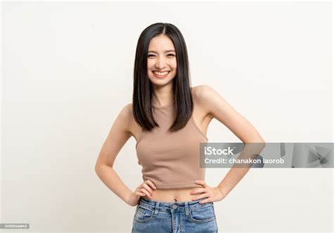 갈색 셔츠를 입은 25세 정도의 아름다운 미소 짓는 행복한 젊은 아시아 여성 고립된 흰색 배경에 서 있는 매력적인 여성 여성 흰색 배경으로 자신감을 갖고 카메라를 보고 있는