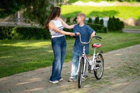 Mother And Son Standing Next To Bicycle Together In Green Park On A
