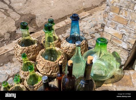 A Variety Of Glass Bottles Some In Woven Baskets Are Displayed Outside The Store Sunlight
