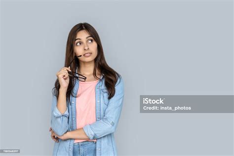 호기심 젊은 성인 인도 여자 복사 공간 회색 배경에 고립 된 서 꿈꾸는 소녀 에 데님 착용 멀리 들고 안경을 들고 불확실한 질문 관심 또는 의심 여자에 대한 스톡 사진 및