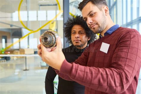 engineers examining robotic gripper arm during industrial automation