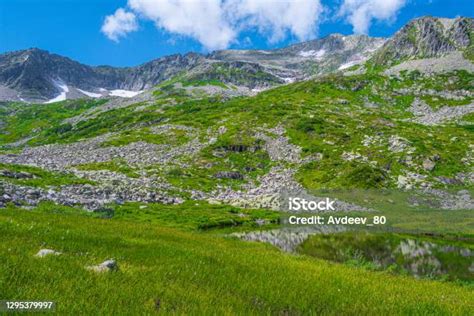 푸른 하늘 아래 눈과 돌 태서와 바위 능선 산악 계곡으로의 여름 여행 녹색 잔디와 돌 초원이있는 대기 고산 풍경 0명에 대한