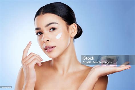 스킨케어 아름다움 그리고 스튜디오에서 파란색 배경에 격리된 크림을 가진 여성의 초상화 화장품 트리트먼트 및 소녀는 로션 자외선 차단제 또는 모이스처 라이저를 얼굴에 바르고