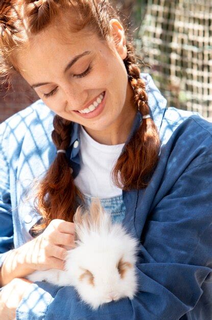 Granjero De Sexo Femenino Que Sostiene Un Conejito Blanco Foto Gratis